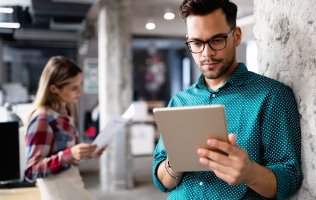 person leaning against wall while on a tablet